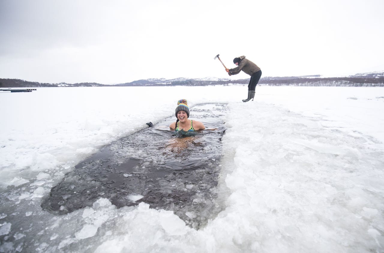 Outdoor swimmer uses sledgehammer to break up ice on frozen loch ...